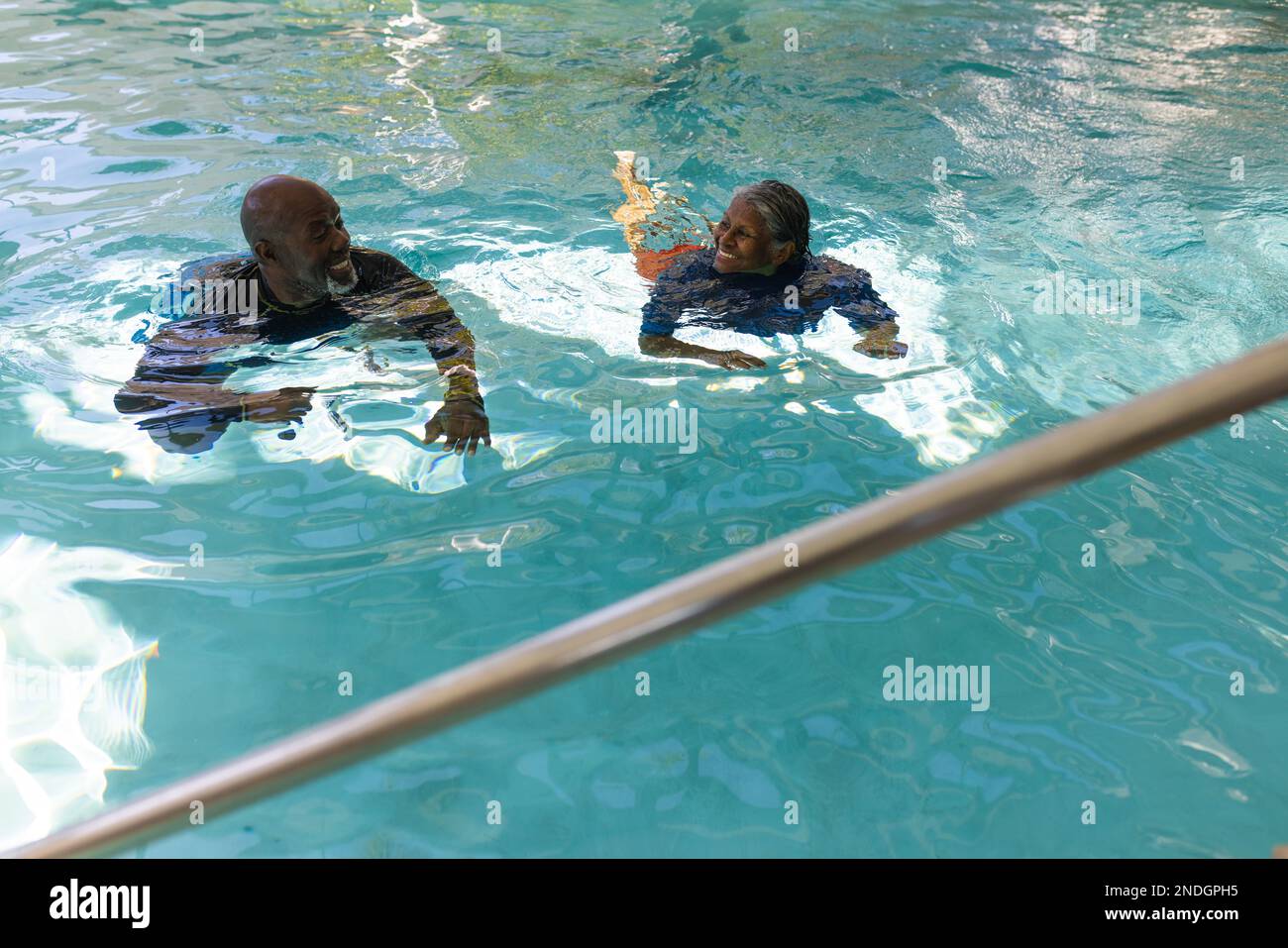 African american senior couple swimming together in the swimming pool ...