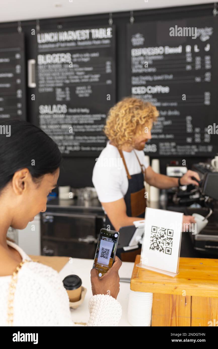 Happy diverse male barista and woman scanning qr code with smartphone ...