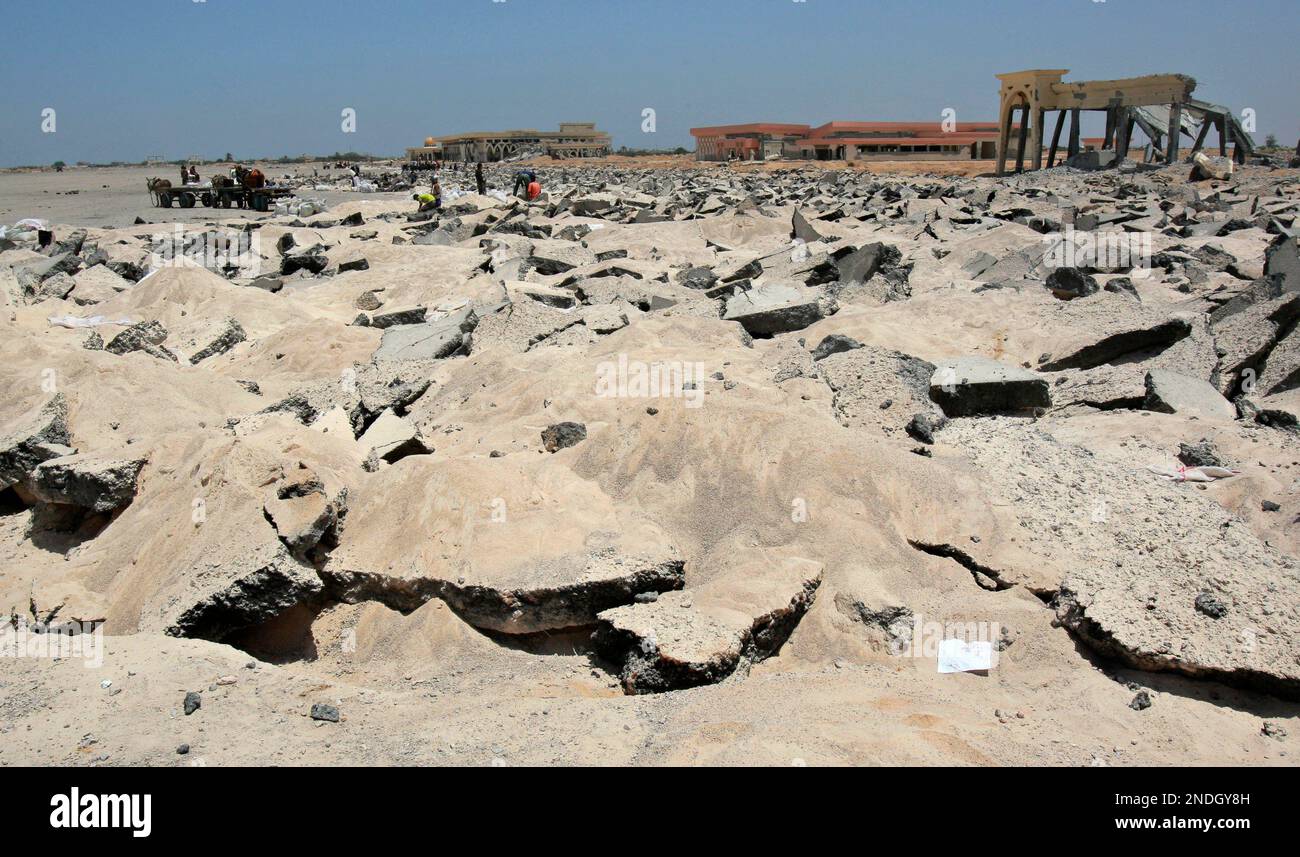 Palestinians search a destroyed runway to collect gravel at the airport ...