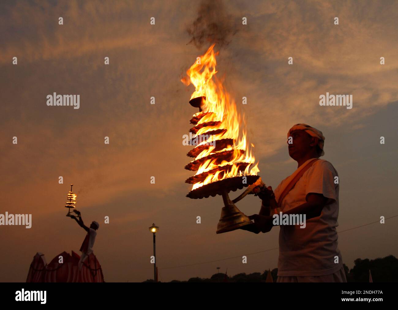 Indian Hindu priests rotate traditional lamps in circular movements as ...