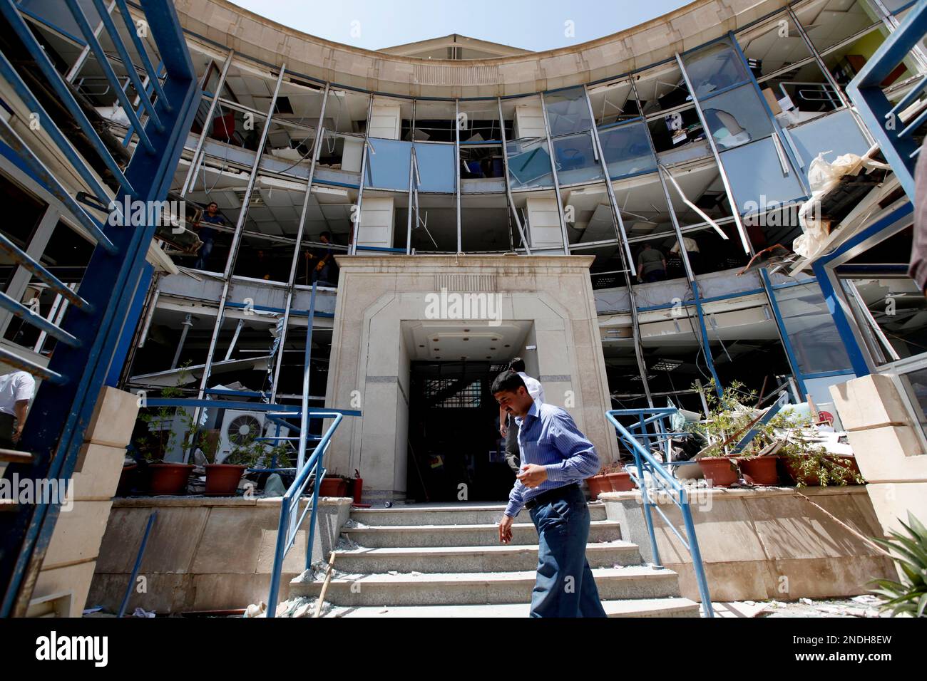 An Iraqi man passes near a bank that was severely damaged in a car bomb ...