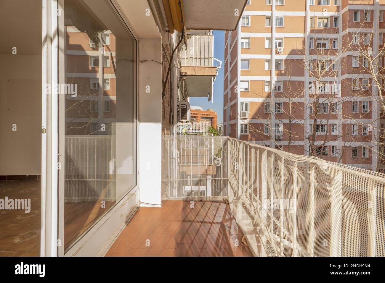 A terrace of a house with a white metal railing and with large glass ...
