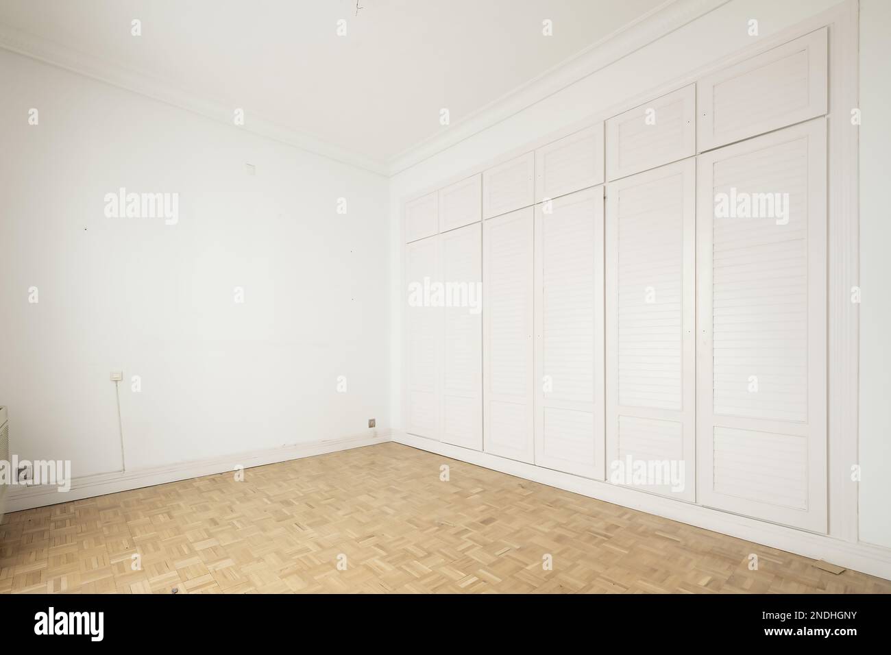 Empty room with one wall covered with white wood cabinets, mezzanine ...