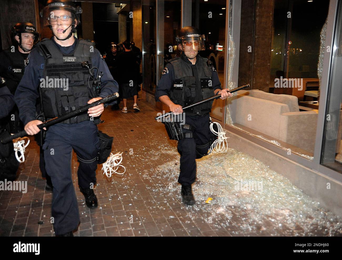 Los Angeles Police Department officers step past a broken window as ...