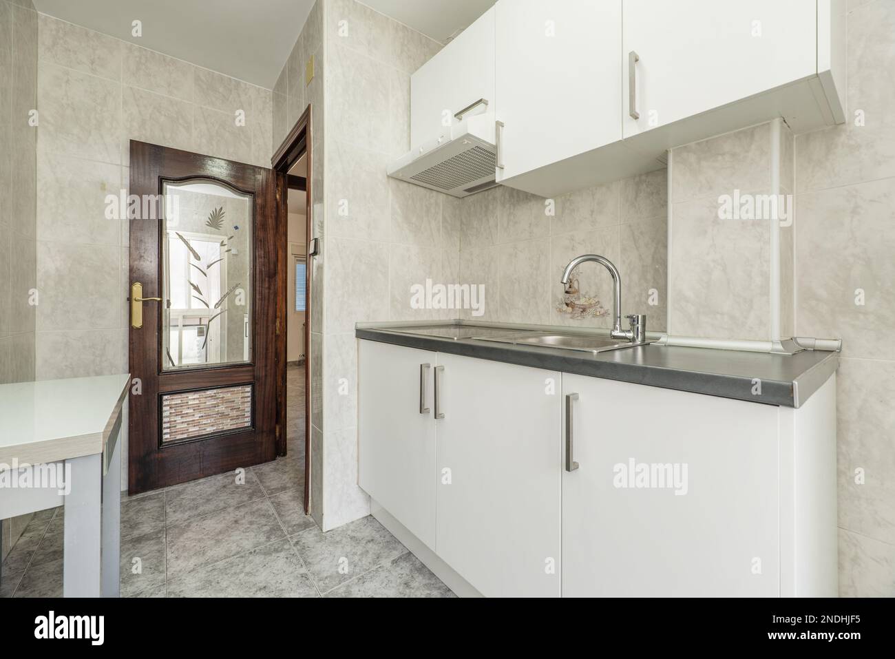 Kitchen equipped along one wall with white cabinets with a gray ...