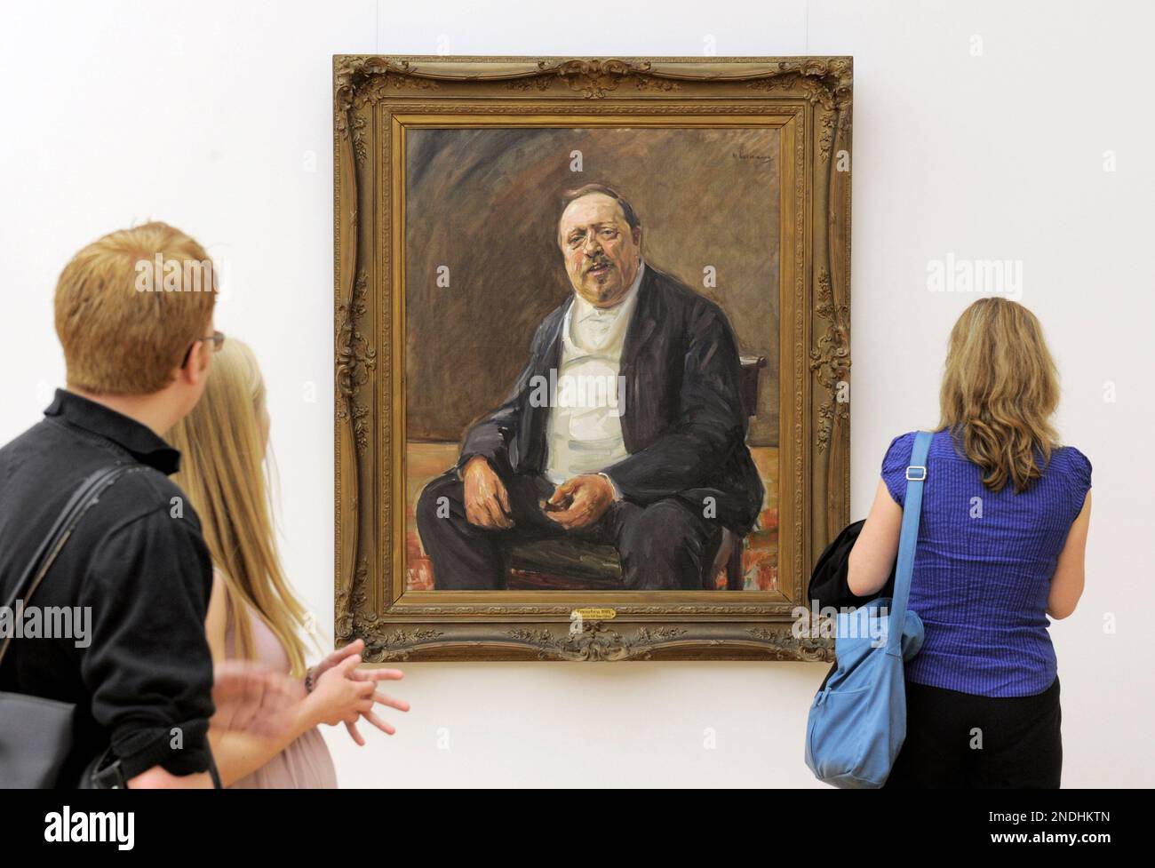 People stand in front of the painting 'Portrait of Alfred von Berger ...