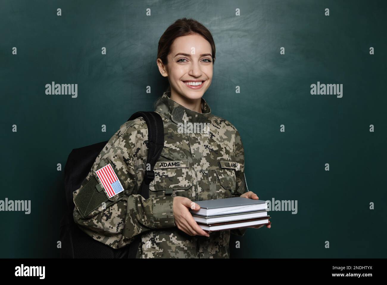 Female cadet with backpack and books near chalkboard. Military ...