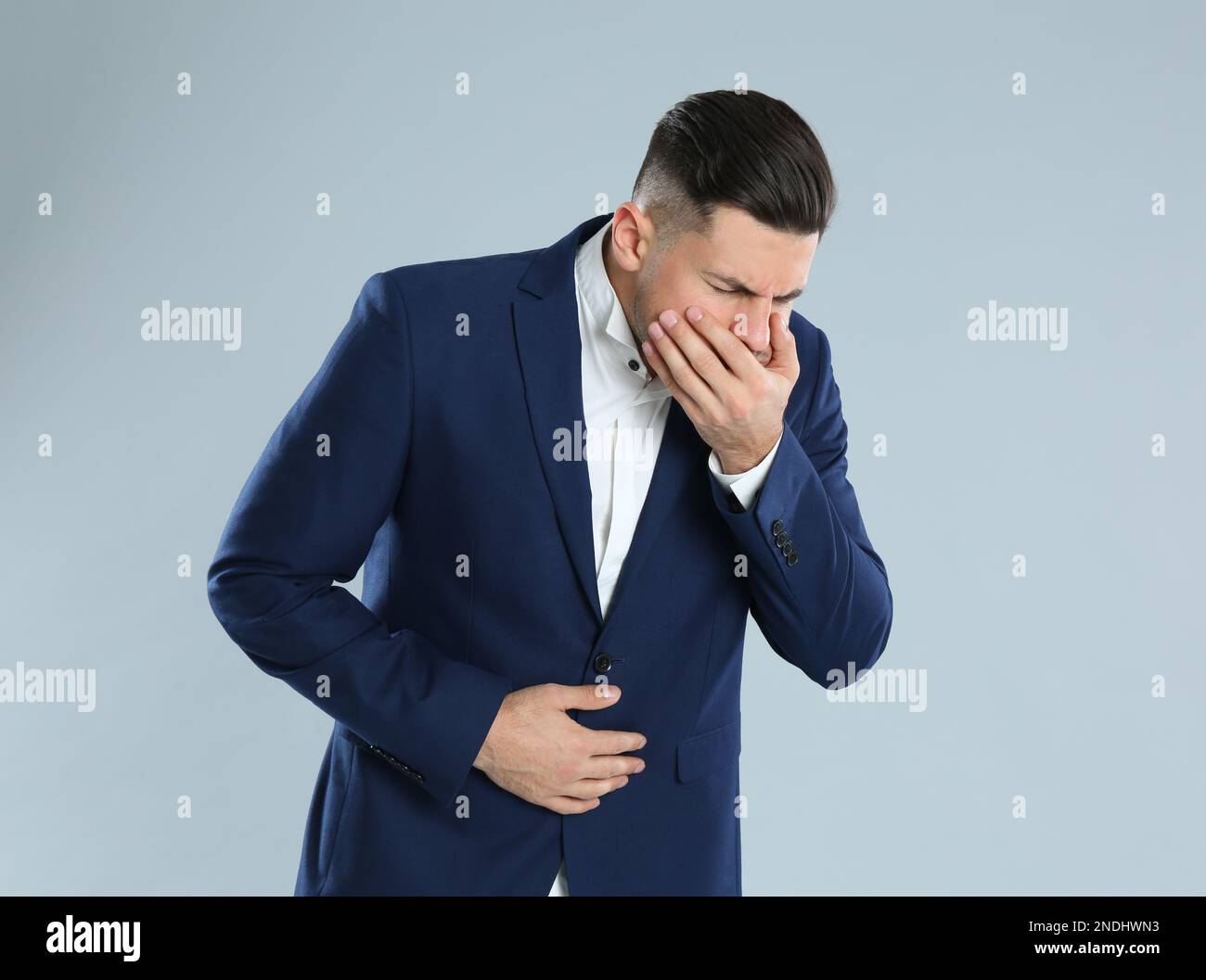 Man in office suit suffering from stomach ache and nausea on grey ...