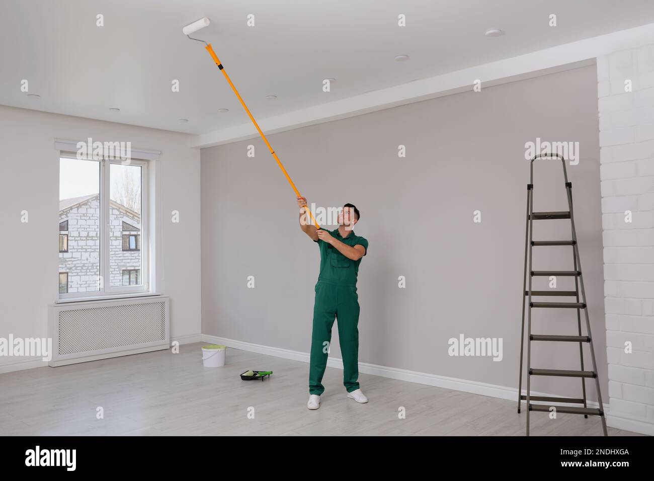 Man painting ceiling with roller in room Stock Photo - Alamy