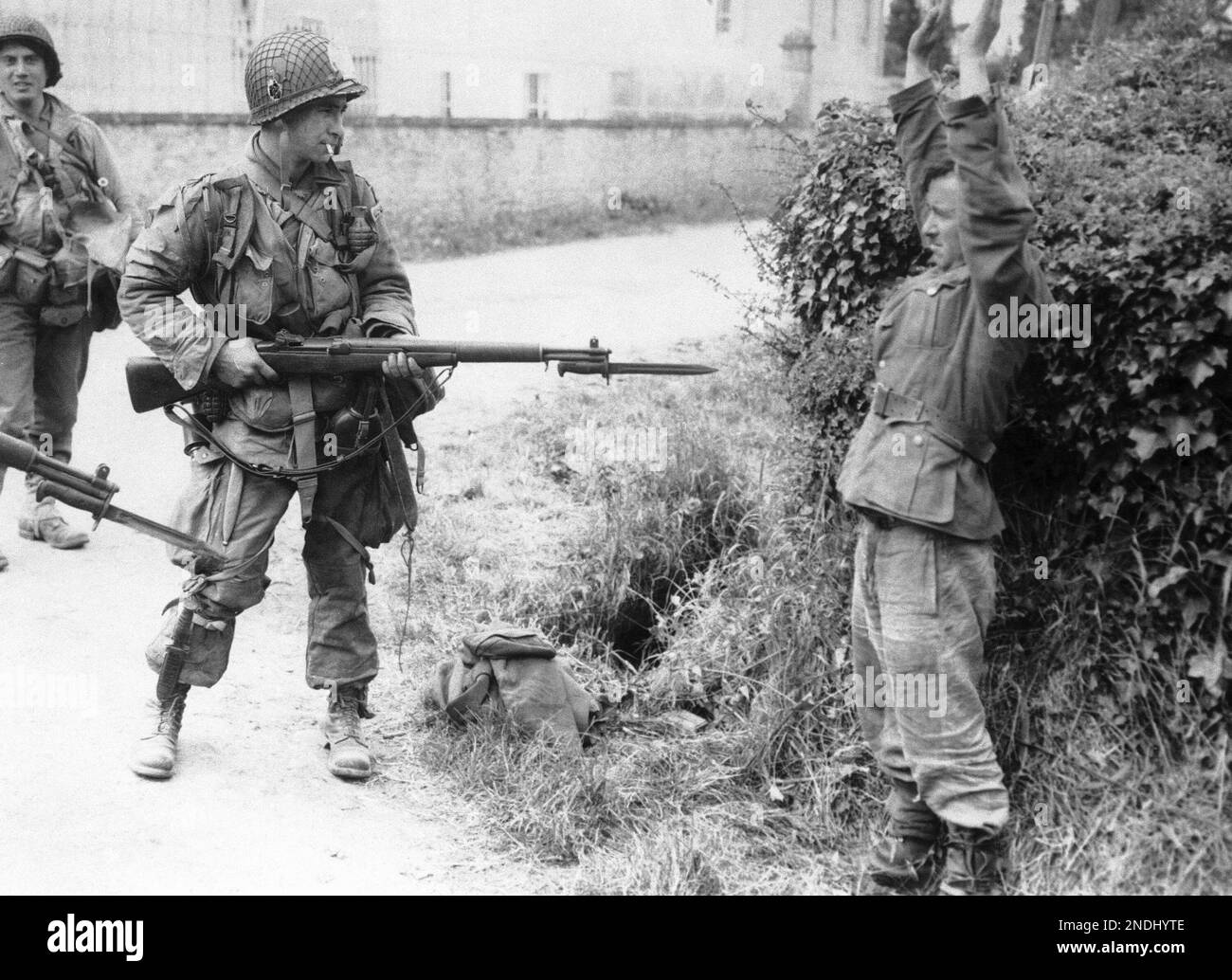 An American paratrooper holds a Nazi prisoner at the point of his ...