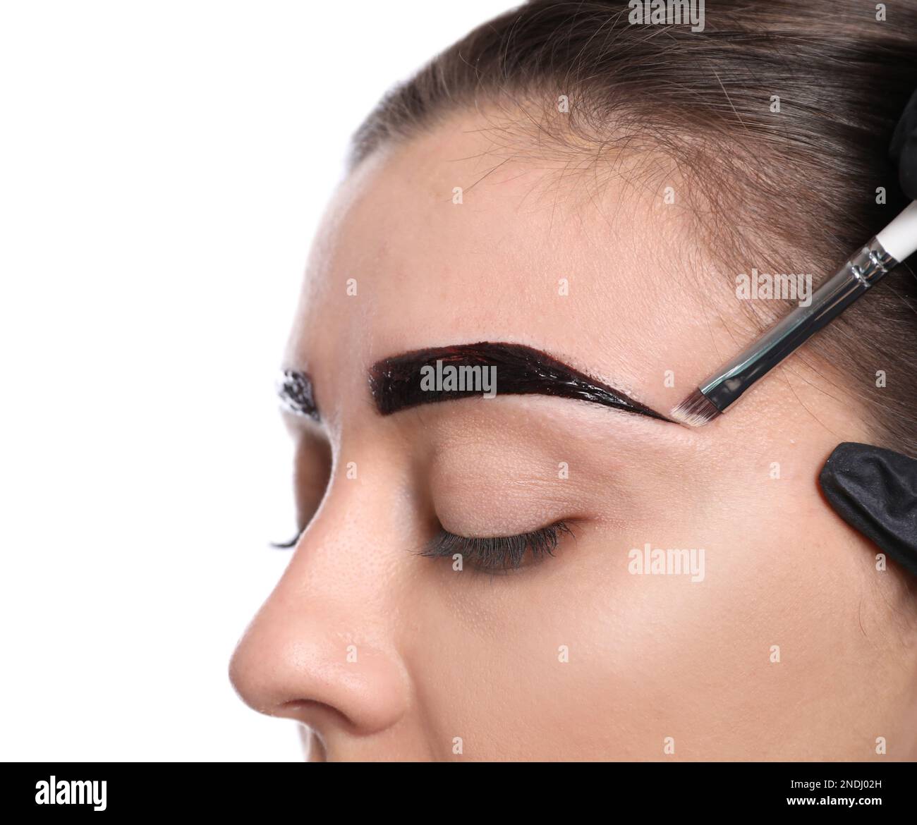 Beautician applying tint during eyebrows correction procedure on white ...