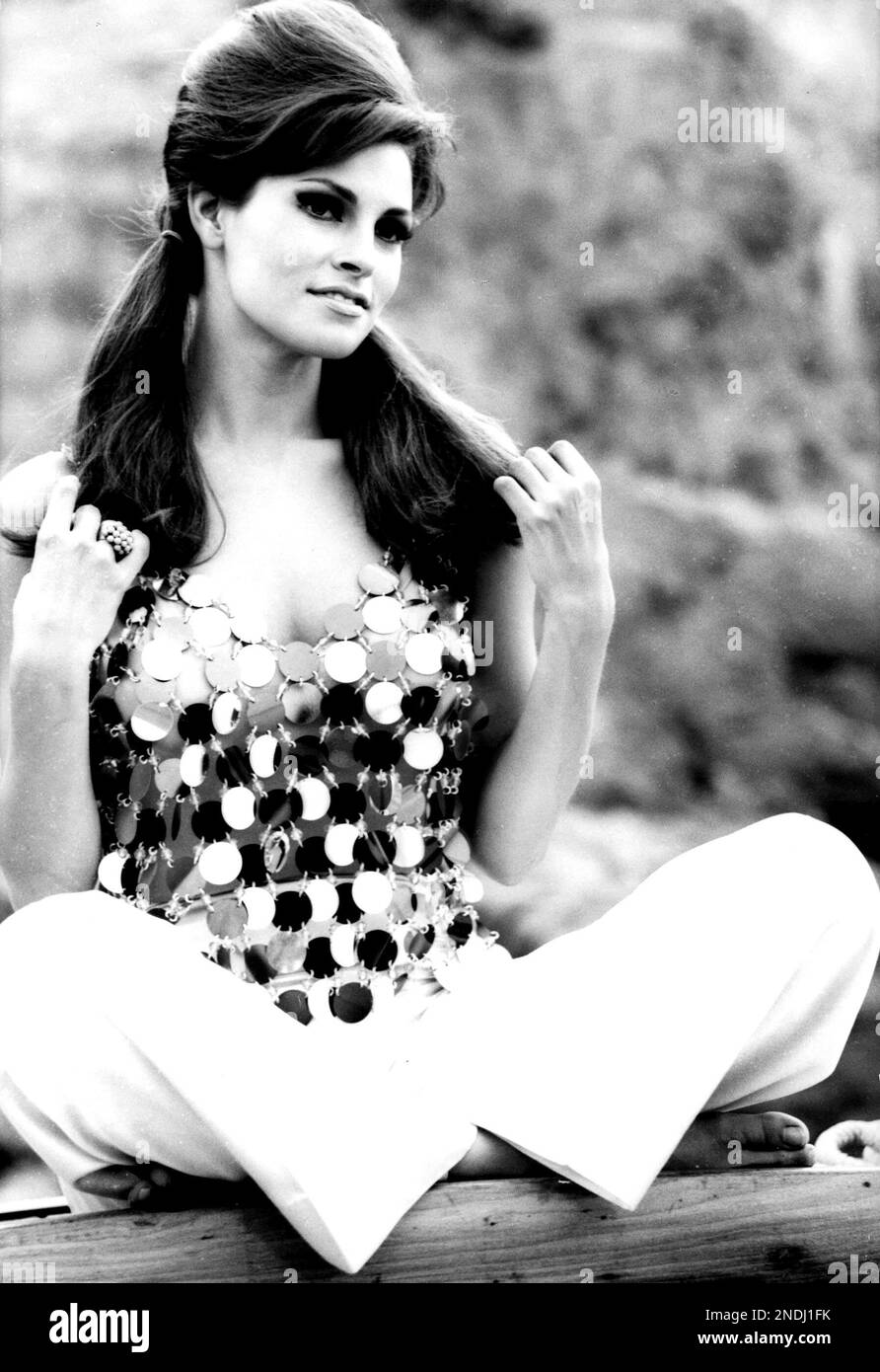 Circa 1975: American actress RAQUEL WELCH sits cross legged outdoors ...