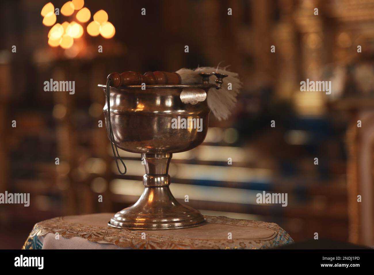 Silver vessel with holy water and brush on stand in church, space for ...