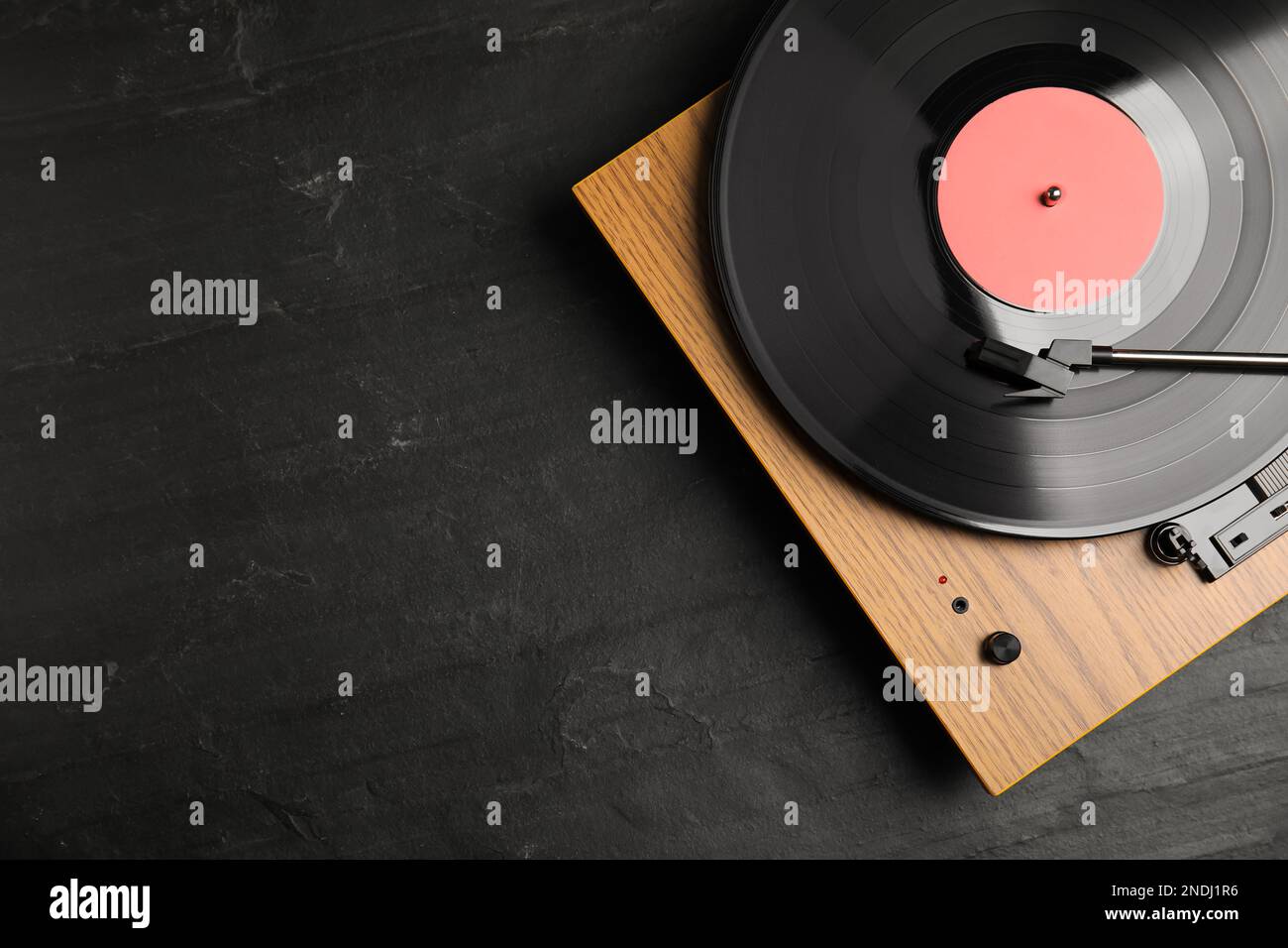 Turntable with vinyl record on black background, top view. Space for ...