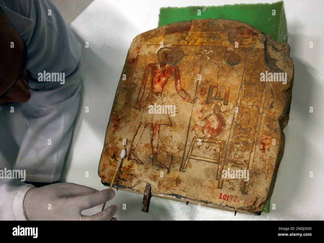 An Egyptian archeological technician works on a pharaonic late period ...