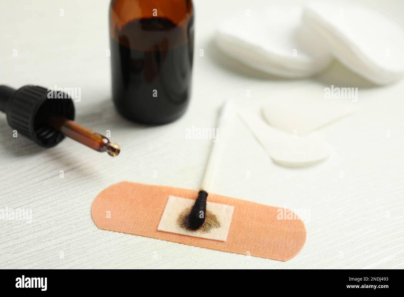 Cotton bud with medical iodine and sticking plaster on white wooden ...
