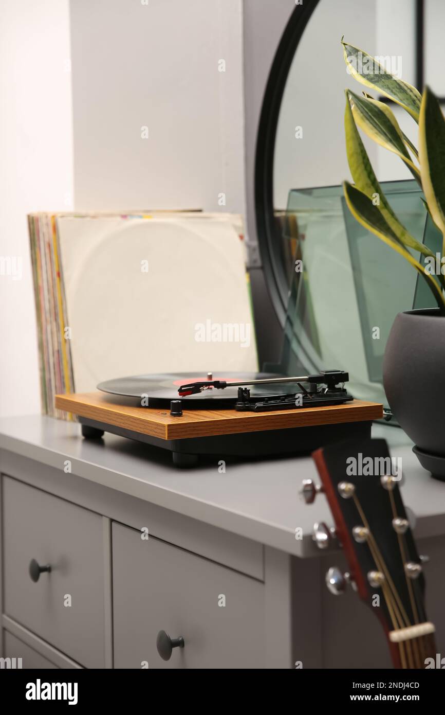 Stylish turntable with vinyl record on chest of drawers indoors Stock ...