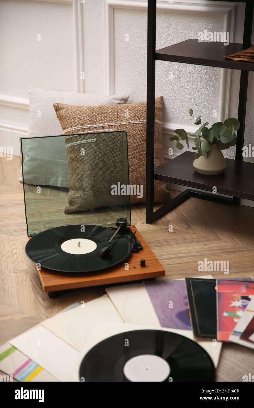 Stylish turntable with vinyl records on floor indoors Stock Photo - Alamy