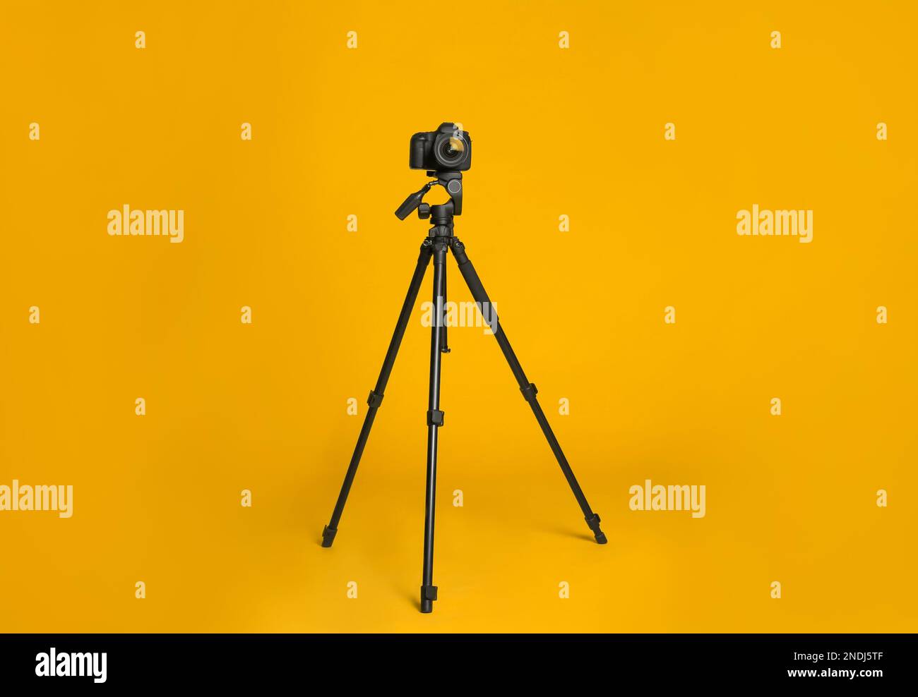 Modern tripod with professional camera on yellow background Stock Photo ...