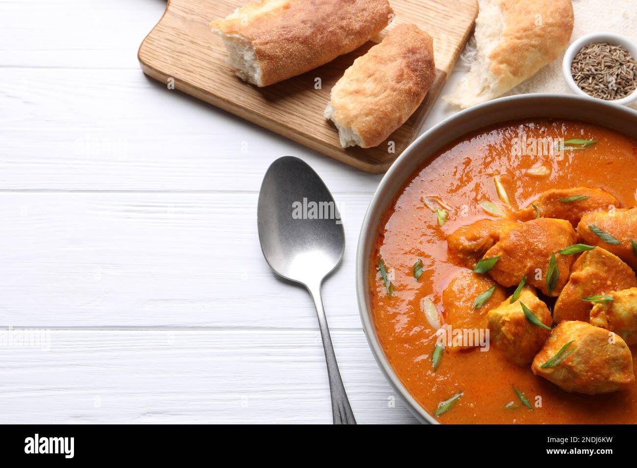 Bowl of delicious chicken curry on white wooden table, above view ...