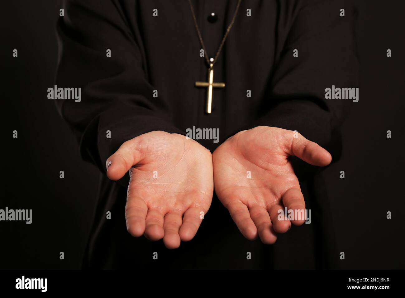 Priest reaching out his hands on black background, closeup Stock Photo ...