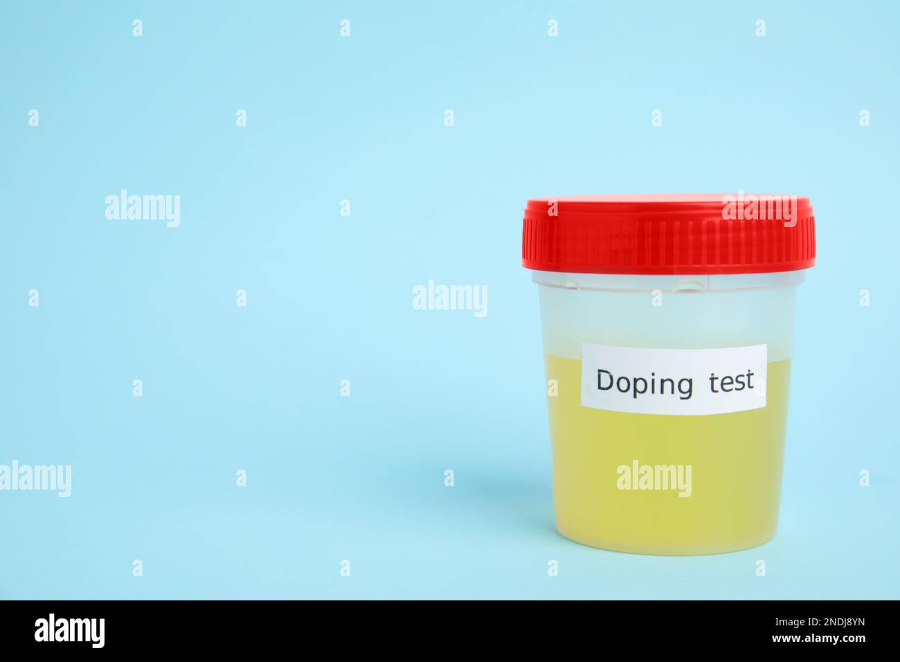 Jar with urine sample on light blue background, space for text. Doping ...