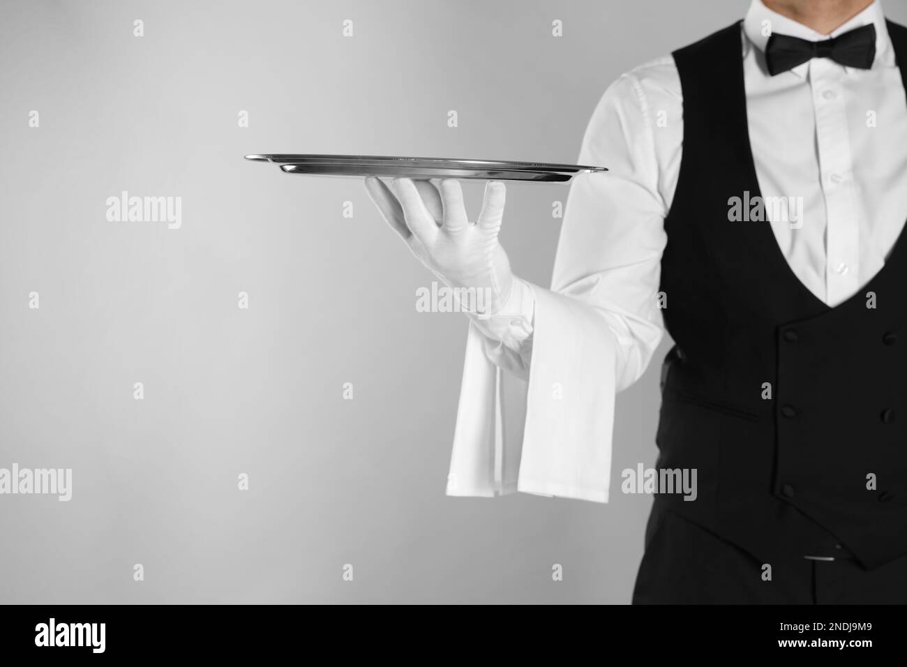 Butler with tray on light grey background, closeup. Space for text ...