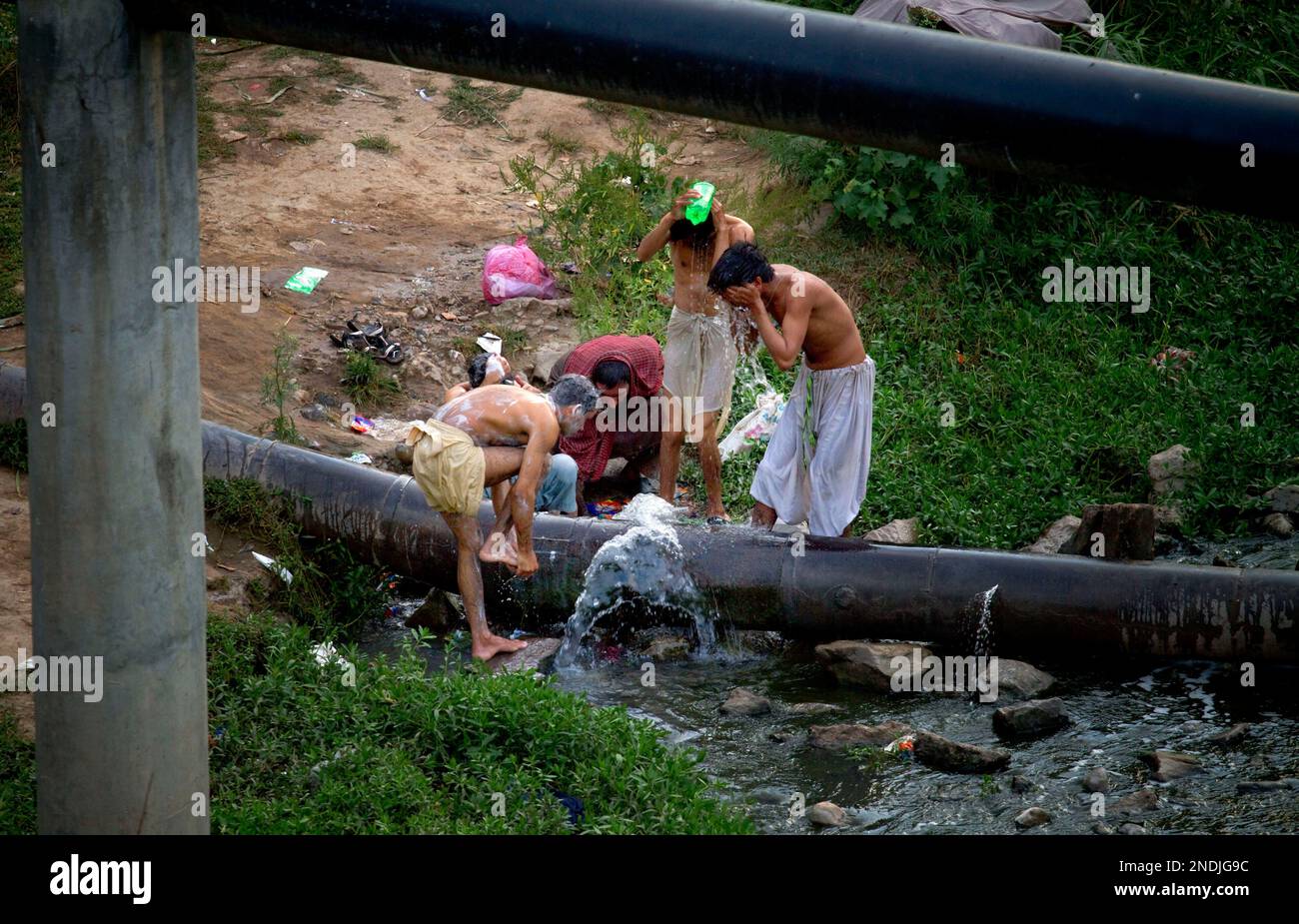 Pakistani laborers perform their ablutions at a leaking water-supply ...