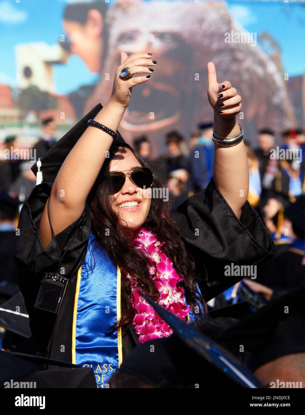 A happy UCLA graduate signals thumbs-up to loved ones in the audience ...
