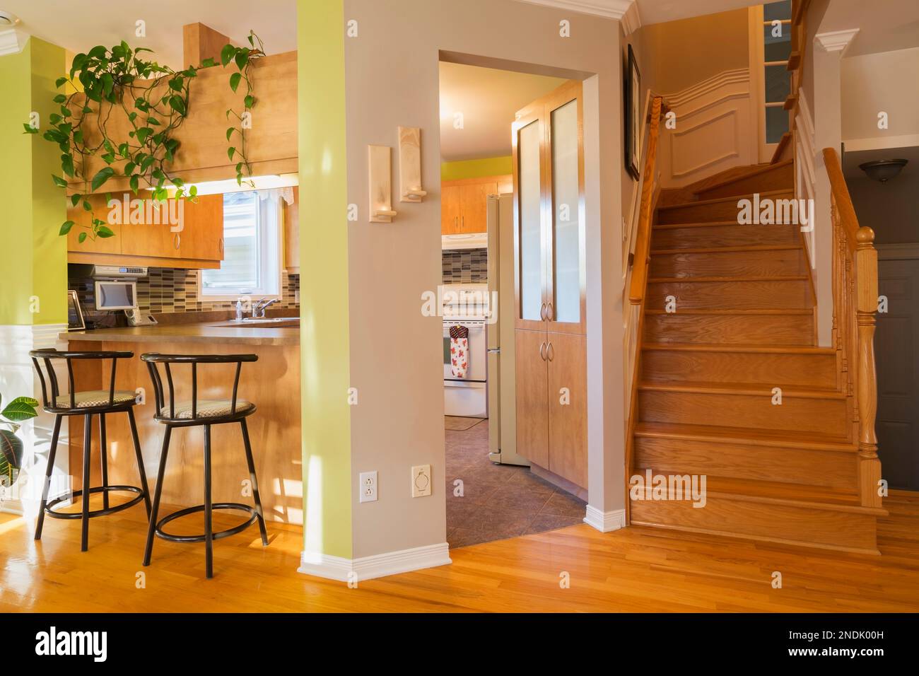 Kitchen counter with barstools and oak wood staircase leading to ...