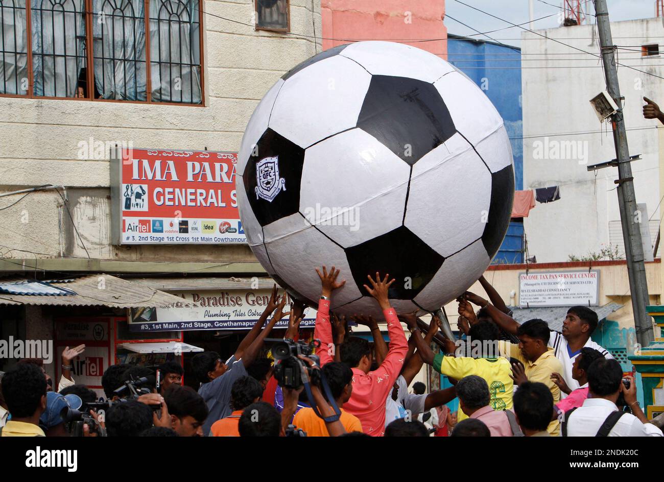 A child peeps from a window as Indian soccer fans lift a giant soccer ...
