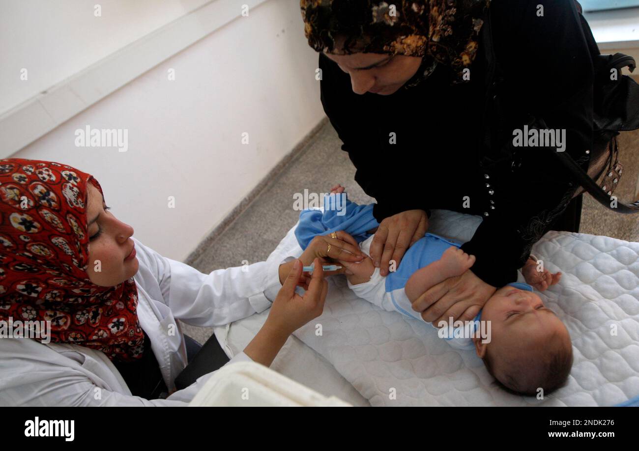In this June 10, 2010 photo, a Palestinian woman helps a nurse to give ...