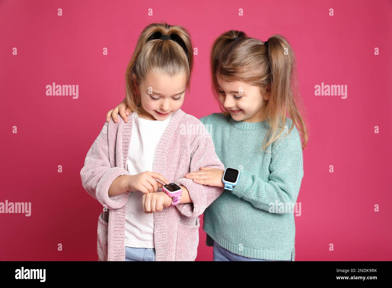 Little girls with smart watches on pink background Stock Photo - Alamy