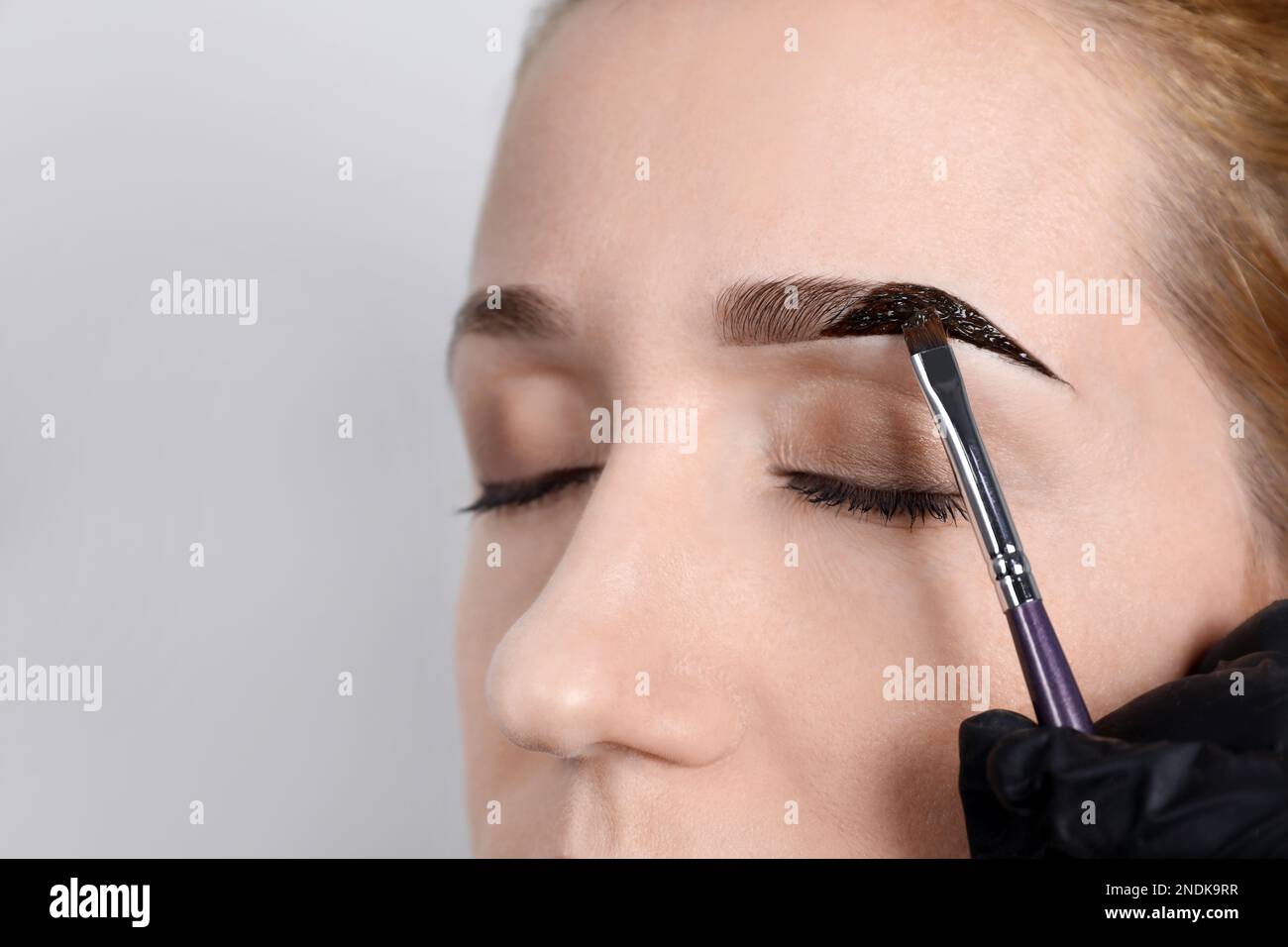 Beautician applying tint during eyebrows correction procedure on light ...