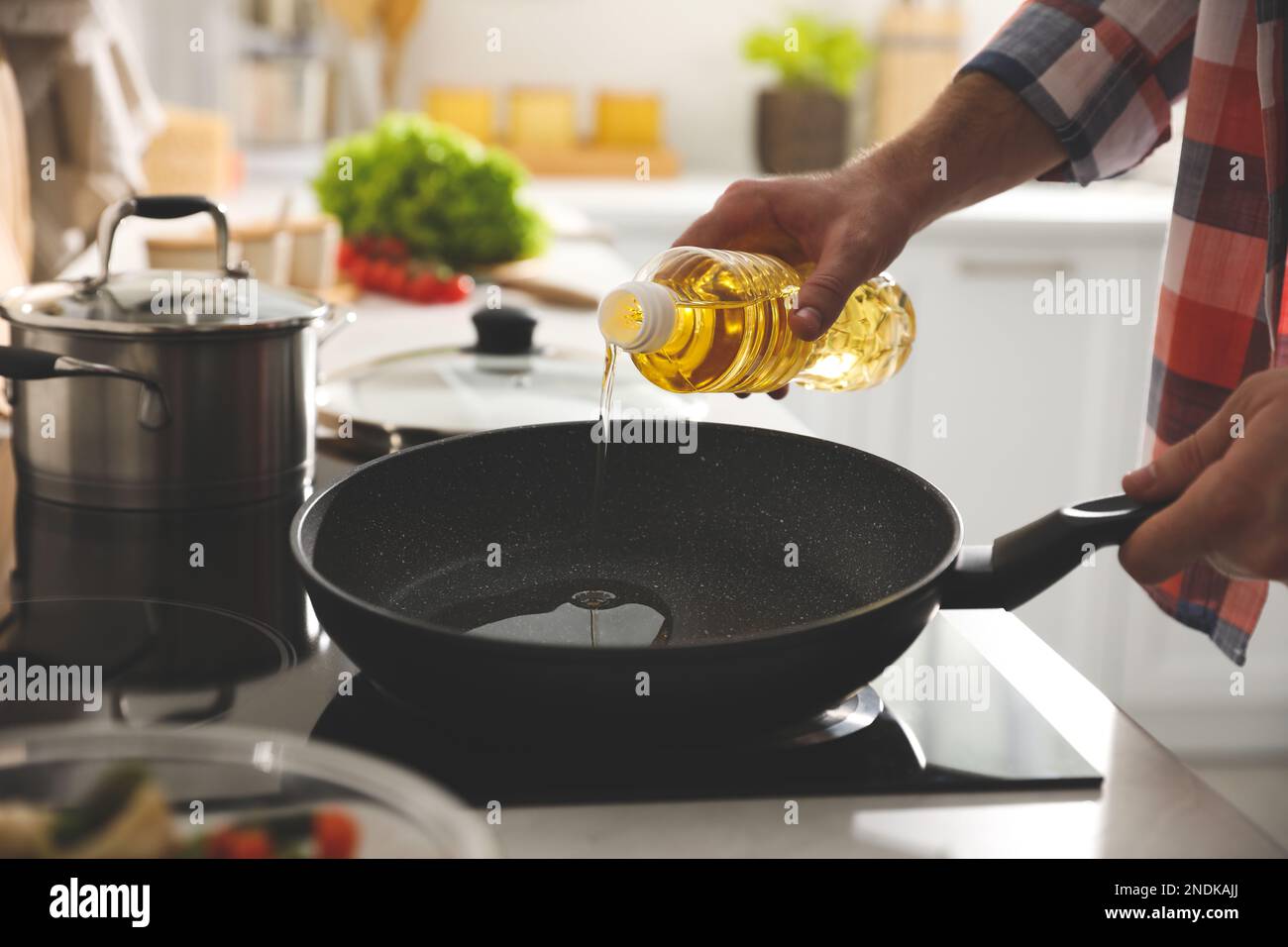 Man pouring cooking oil into frying pan in kitchen, closeup Stock Photo ...