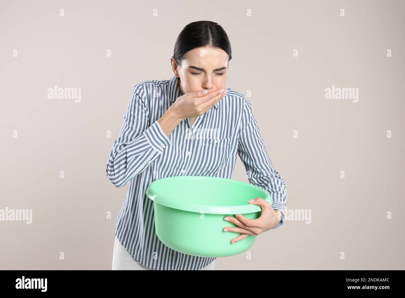 Woman with basin suffering from nausea on beige background. Food ...