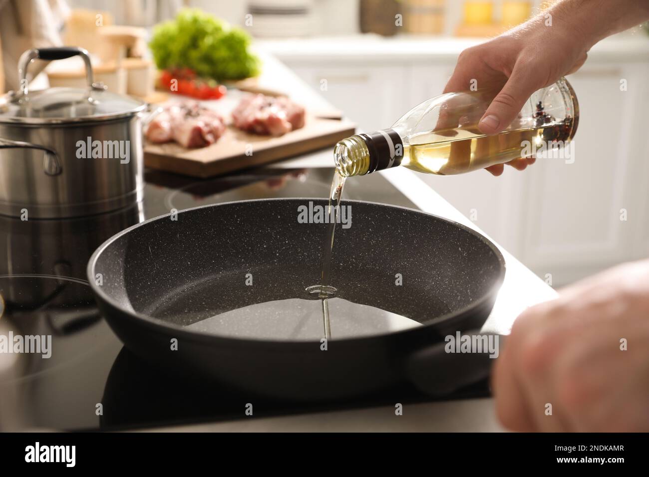 Man pouring cooking oil into frying pan in kitchen, closeup Stock Photo ...