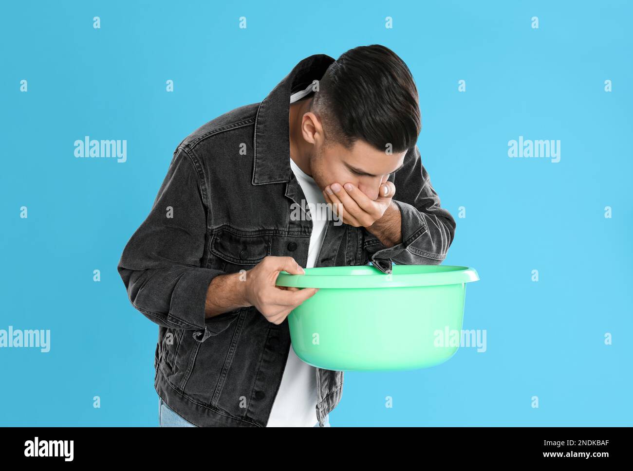 Man with basin suffering from nausea on light blue background. Food ...