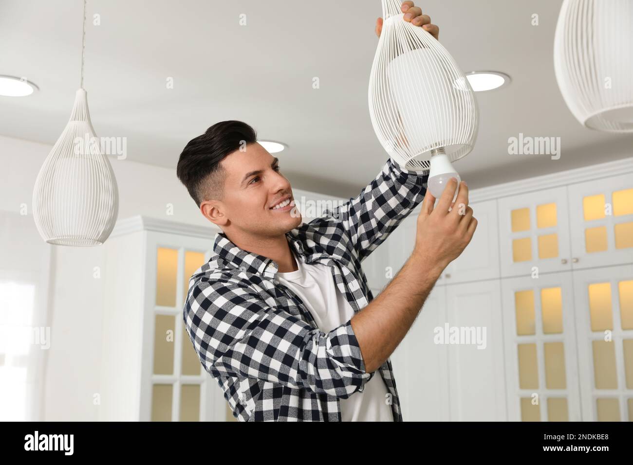 Man changing light bulb in lamp at home Stock Photo - Alamy