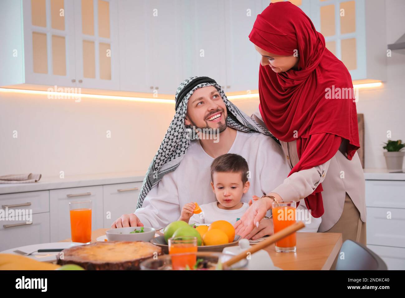 Happy Muslim family eating together in kitchen, space for text Stock ...