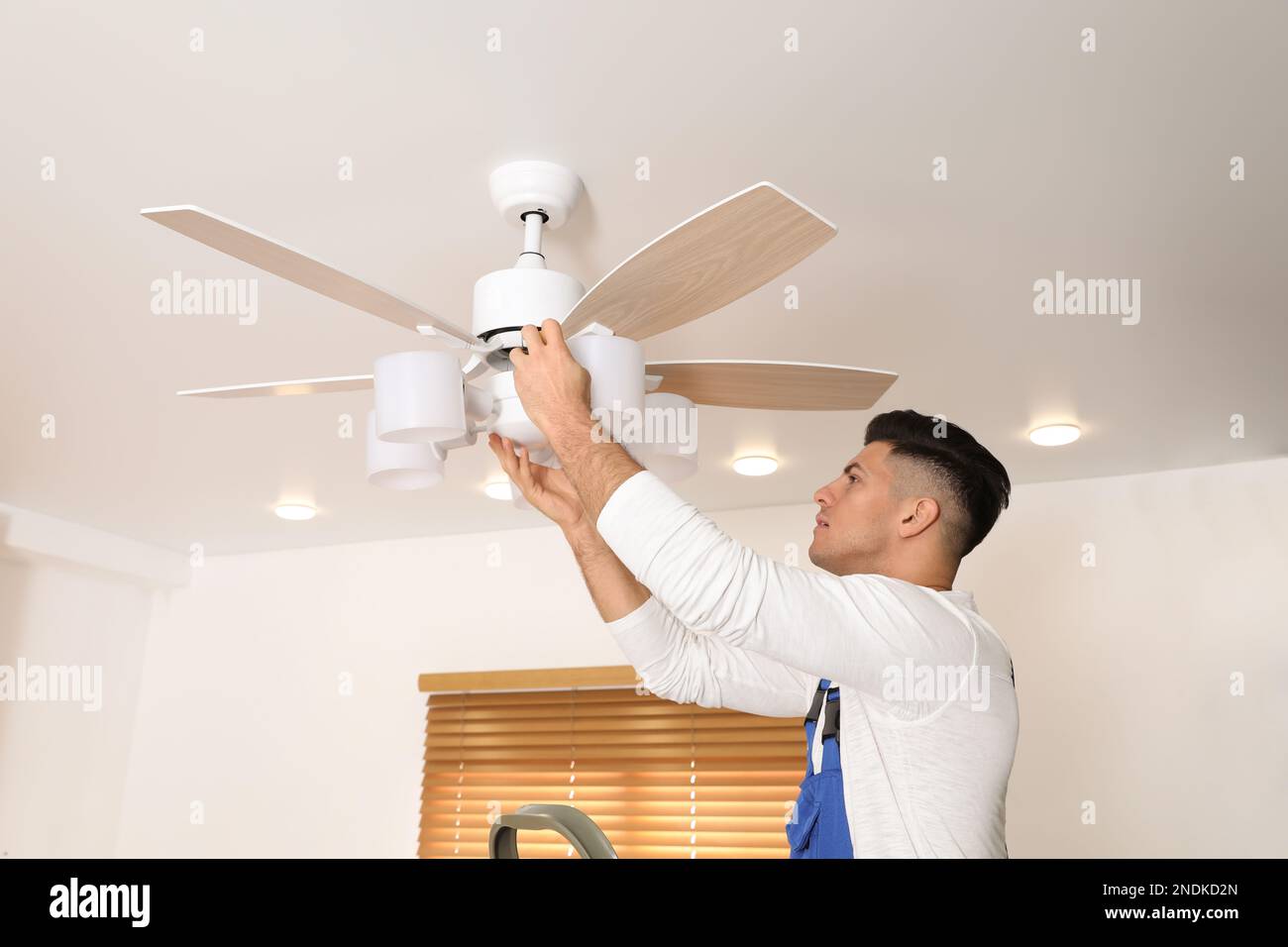 Electrician repairing ceiling fan with lamps indoors Stock Photo - Alamy