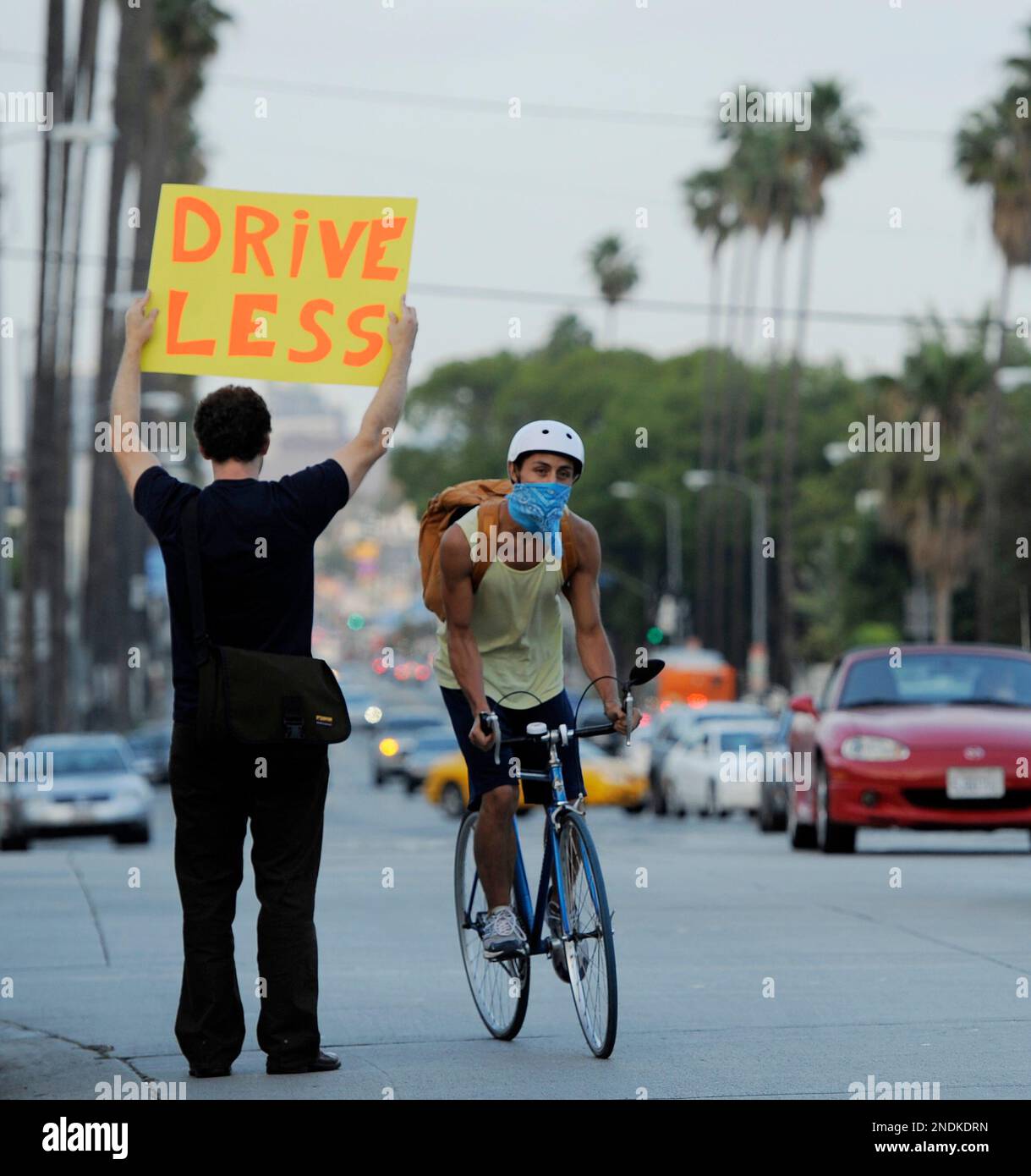 A cyclist rides past Jed Ela, left, of Los Angeles, as he participates ...