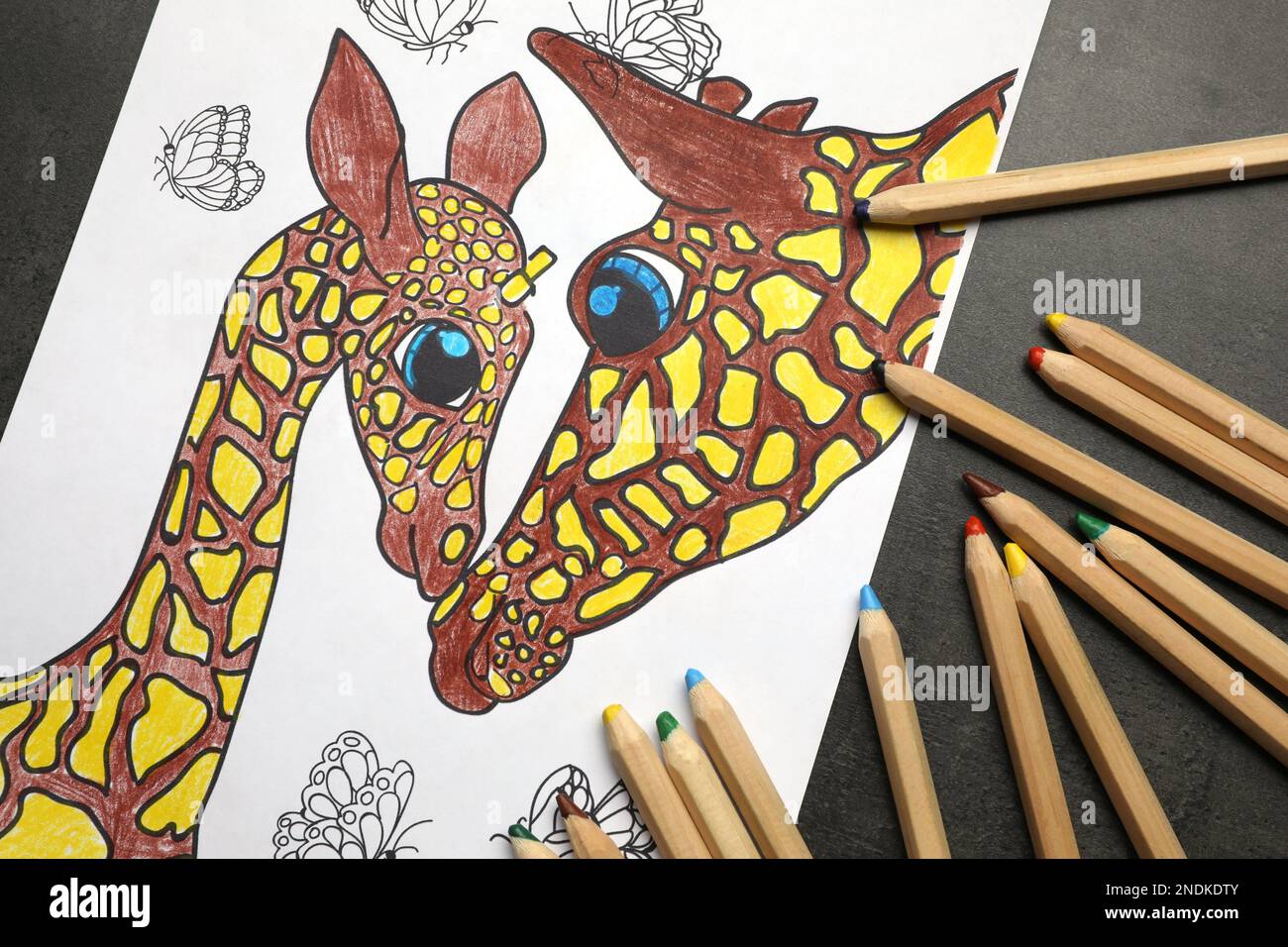 Coloring page with children drawing and set of pencils on grey table ...