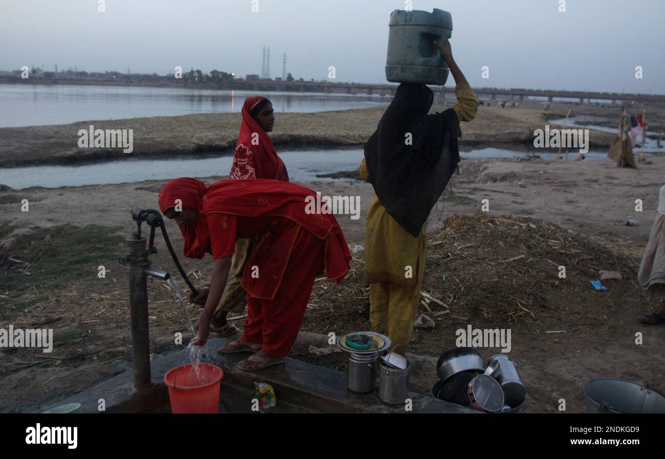 Pakistani women fetch water from a tubewell at a riverside in Lahore ...