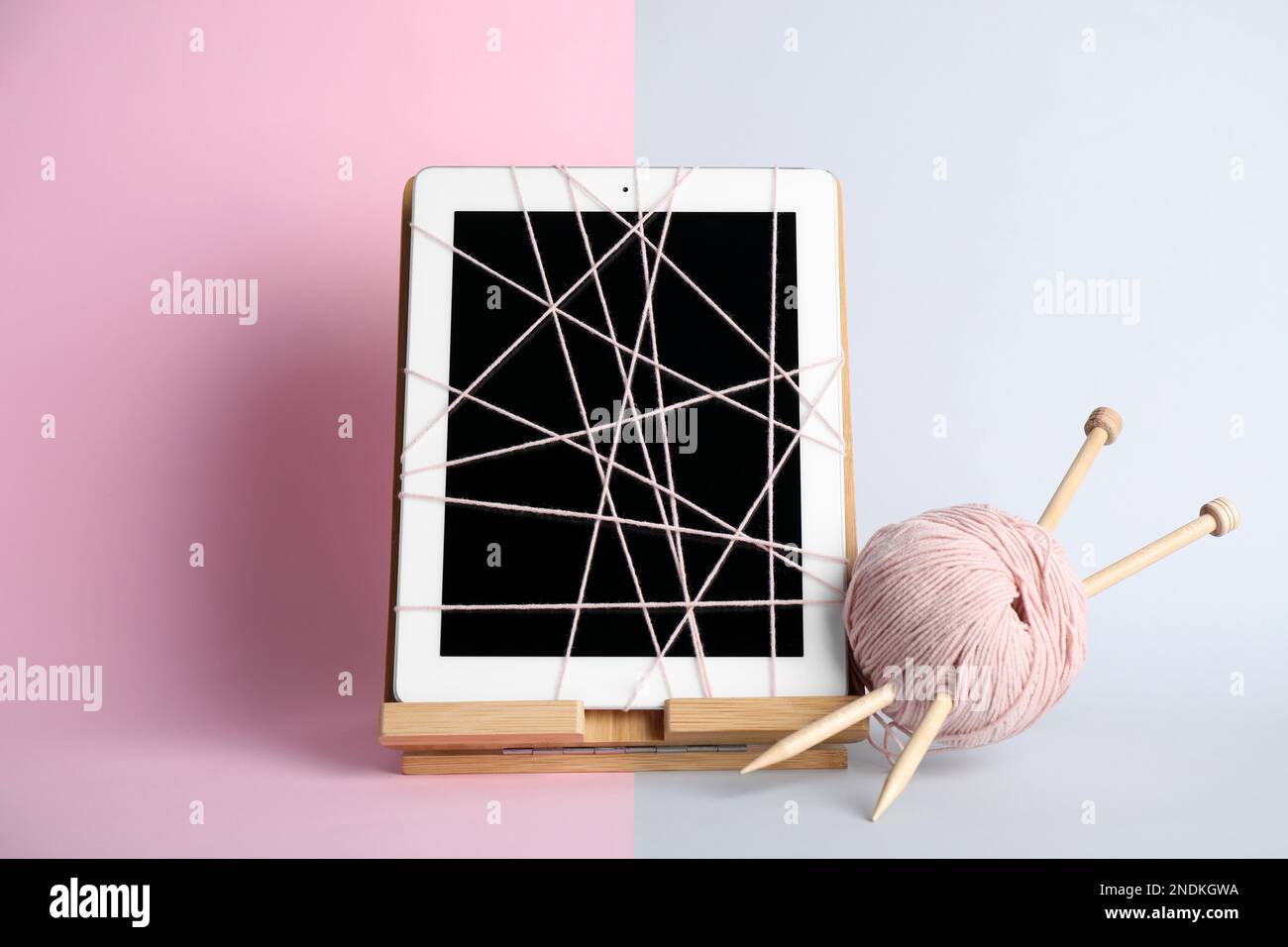 Modern tablet wrapped in thread, yarn ball and knitting needles on ...