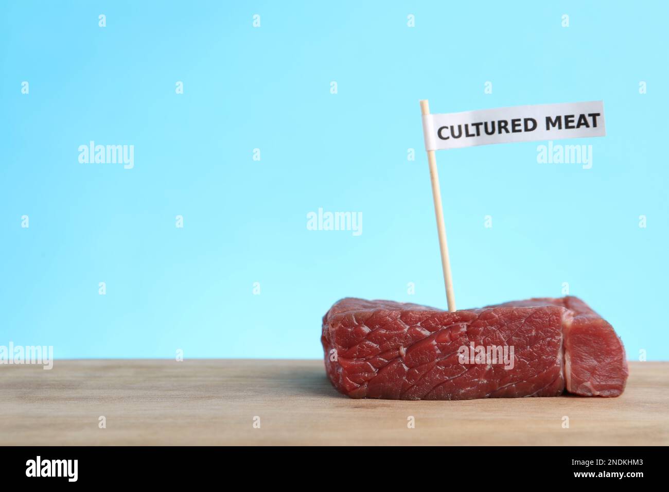 Sample of lab grown beef labeled Cultured Meat on wooden table. Space ...