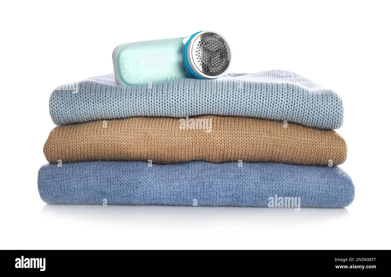Modern fabric shaver and woolen clothes on white background Stock Photo ...