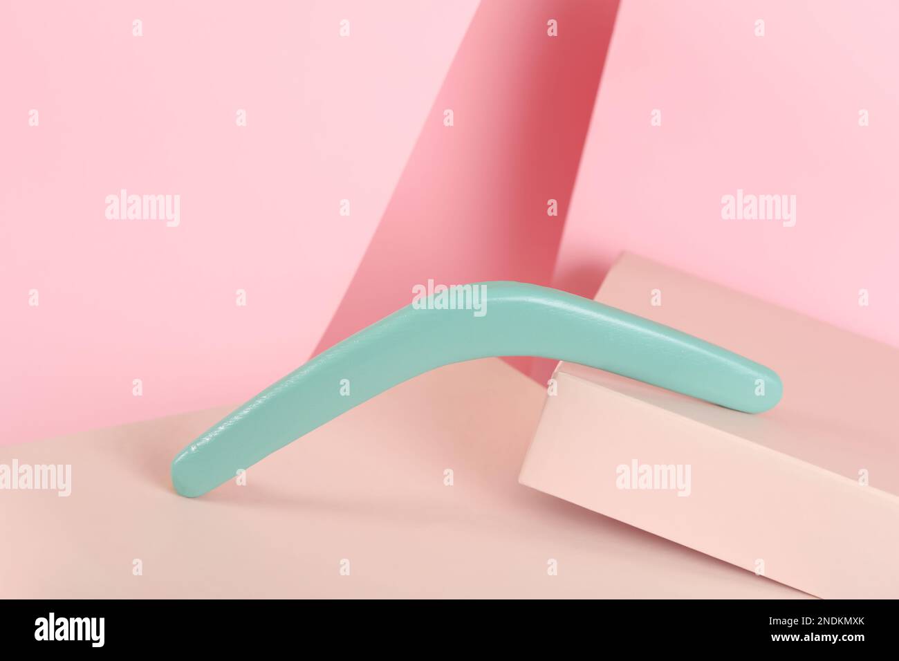 Creative composition with turquoise wooden boomerang on pink background ...