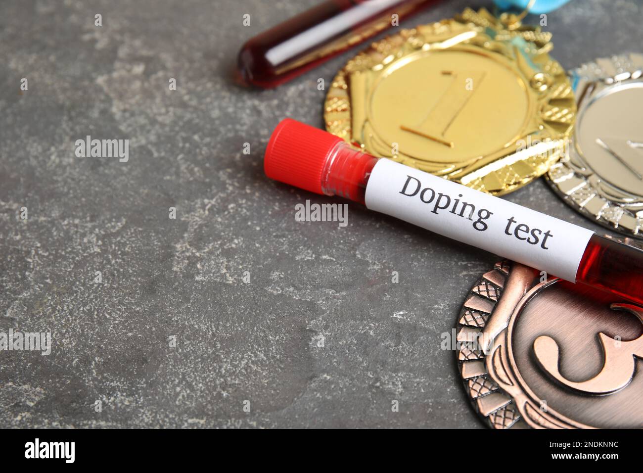Medals and tube of blood with words Doping test on grey stone table ...