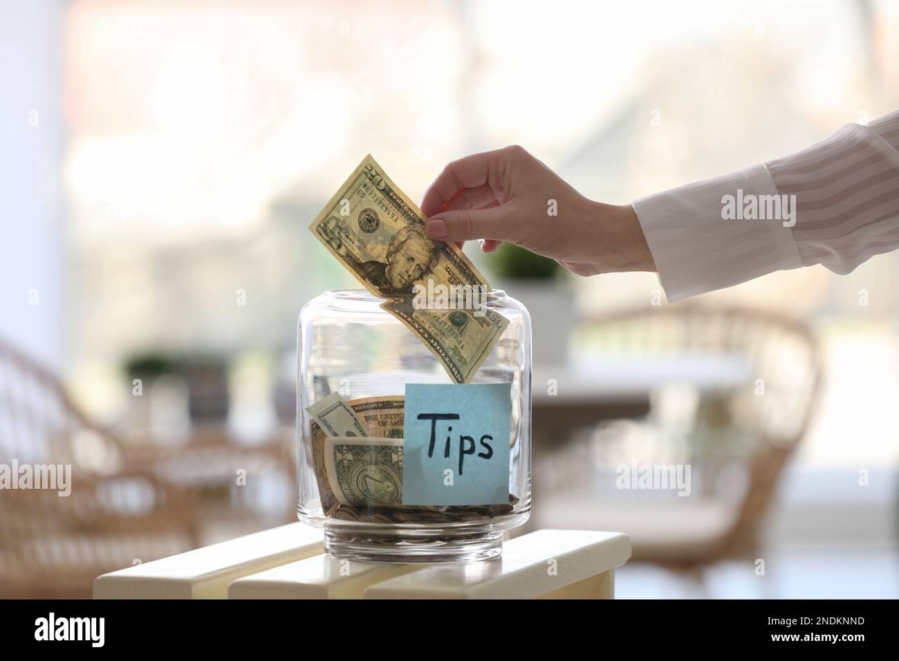 Woman putting tips into glass jar at table, closeup Stock Photo - Alamy